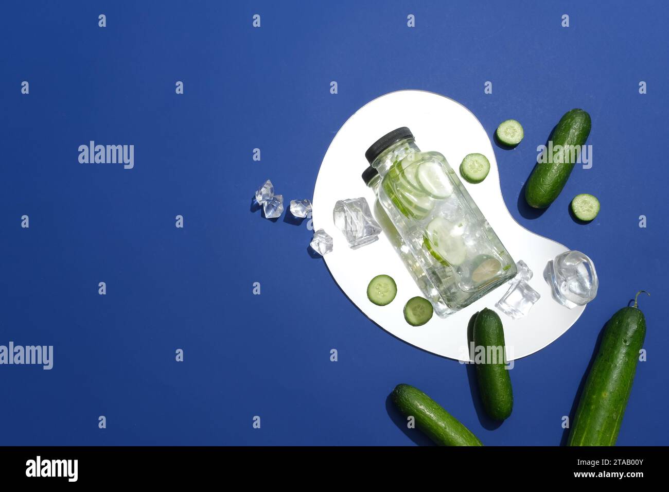 A bottle filled with cucumber detox water placed on a mirror, decorated ...