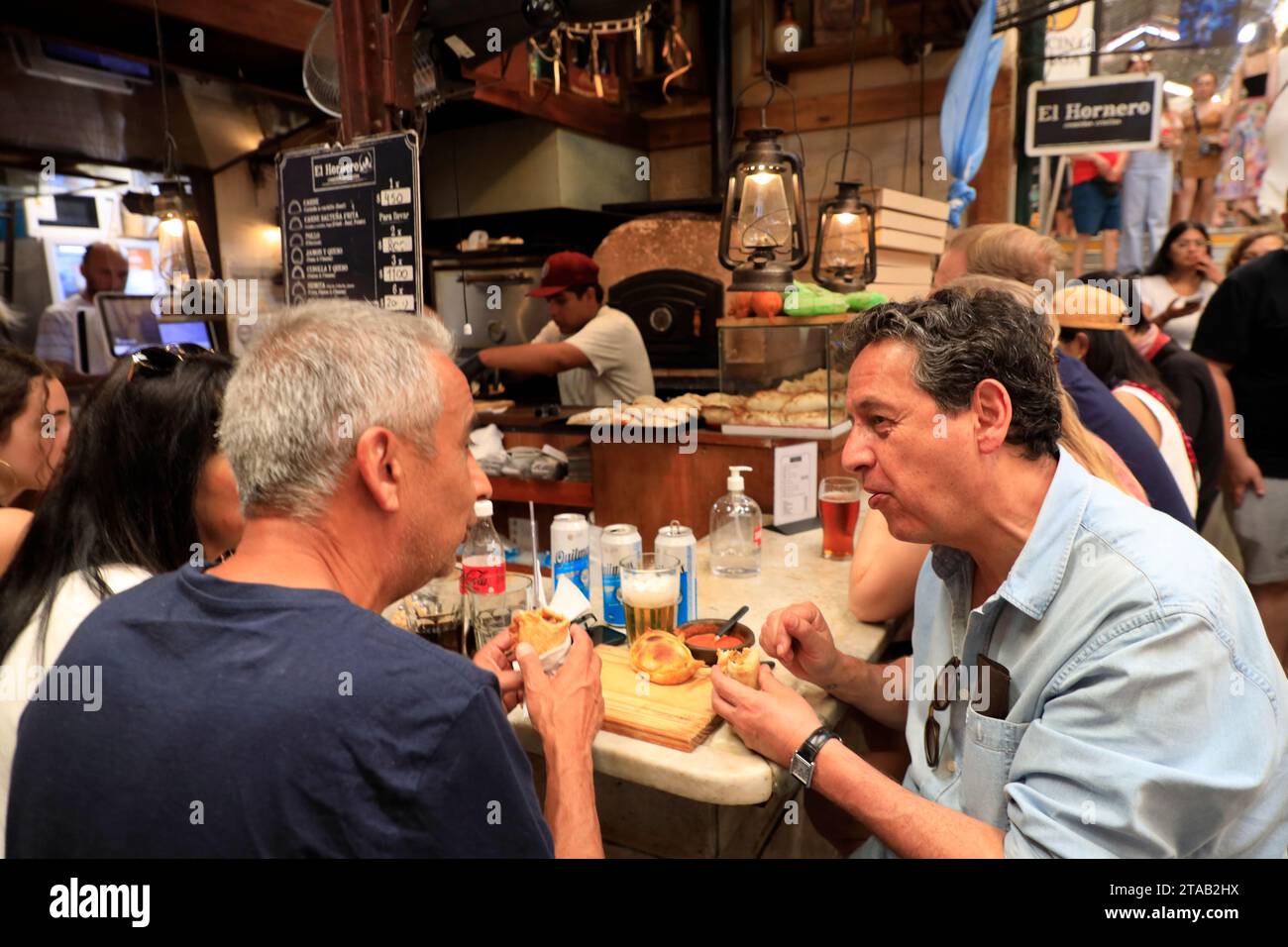 Customers having lunch by a open kitchen in a grill restaurant inside ...