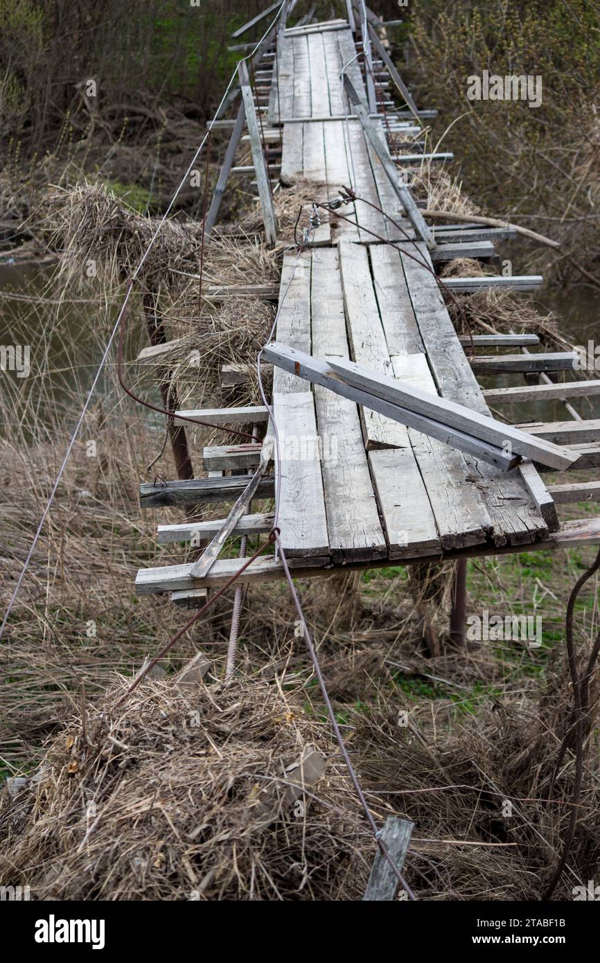 A broken pedestrian suspension bridge in the countryside after a spring ...