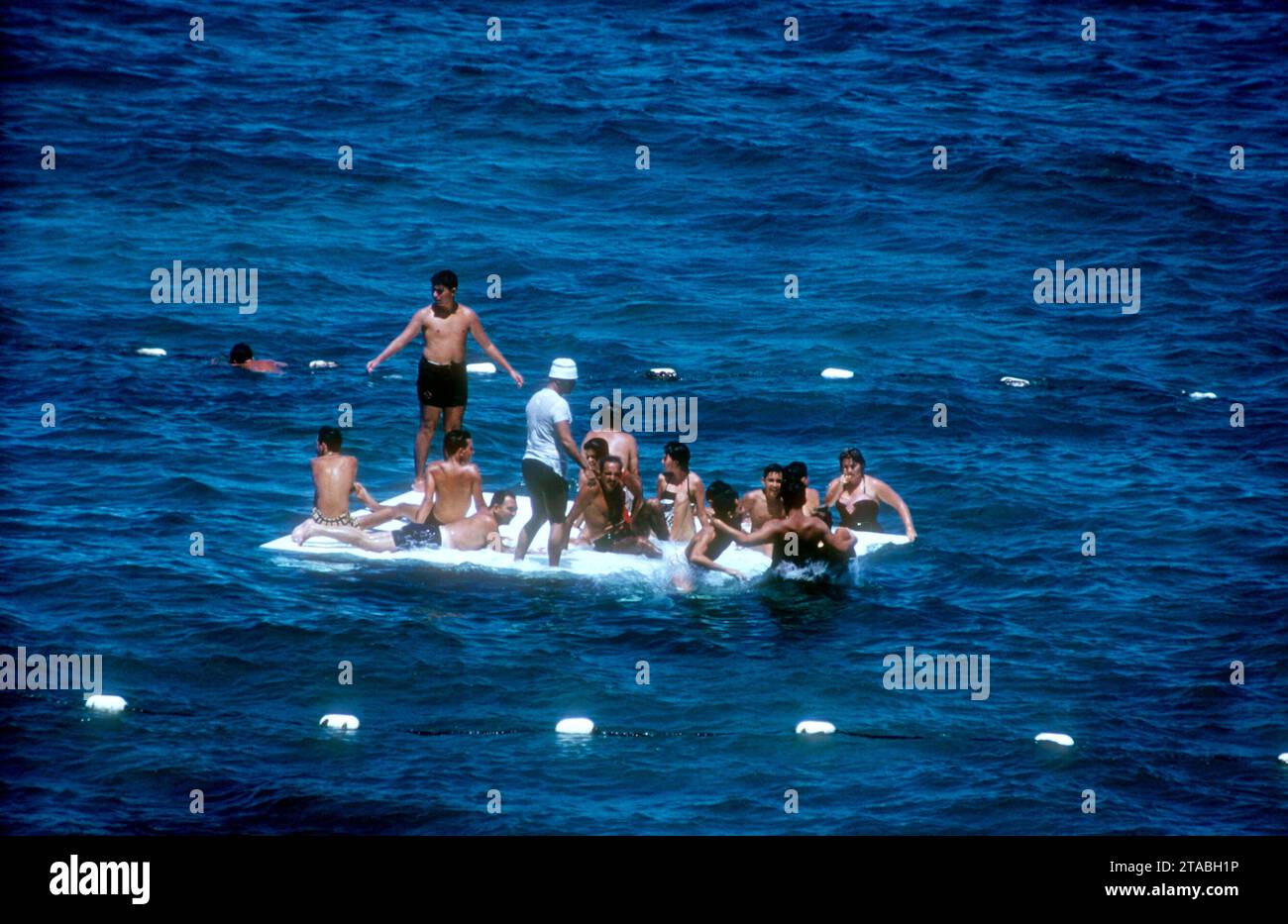 LAKELAND, FL - AUGUST, 1955: A group of people sit on a raft to watch ...