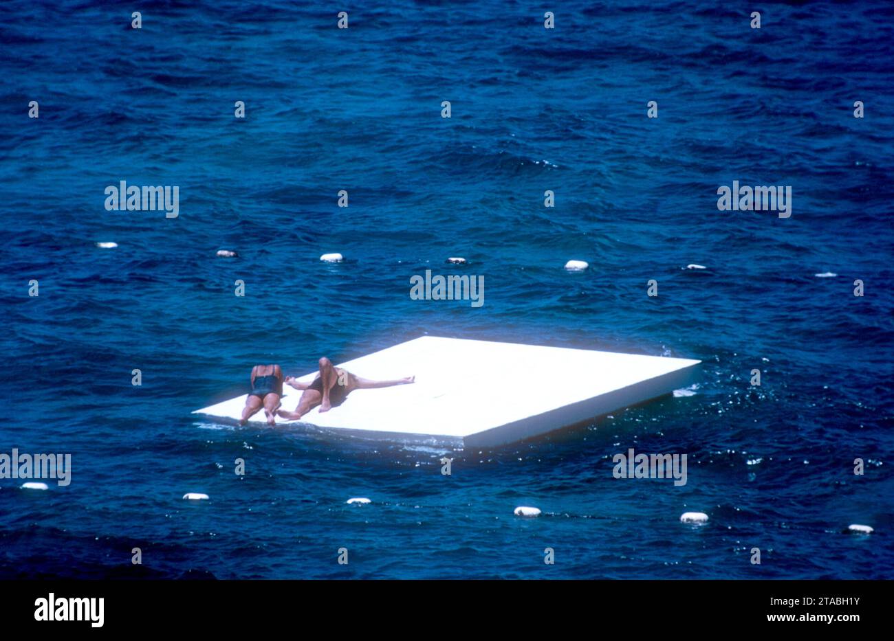 LAKELAND, FL - AUGUST, 1955: A man and woman lay out on a raft to watch ...