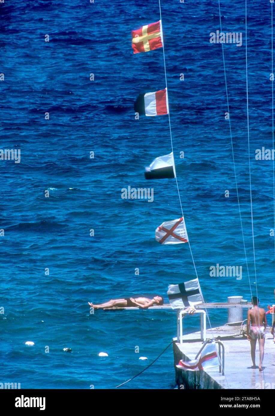 LAKELAND, FL - AUGUST, 1955: A man lays out on a diving board before ...