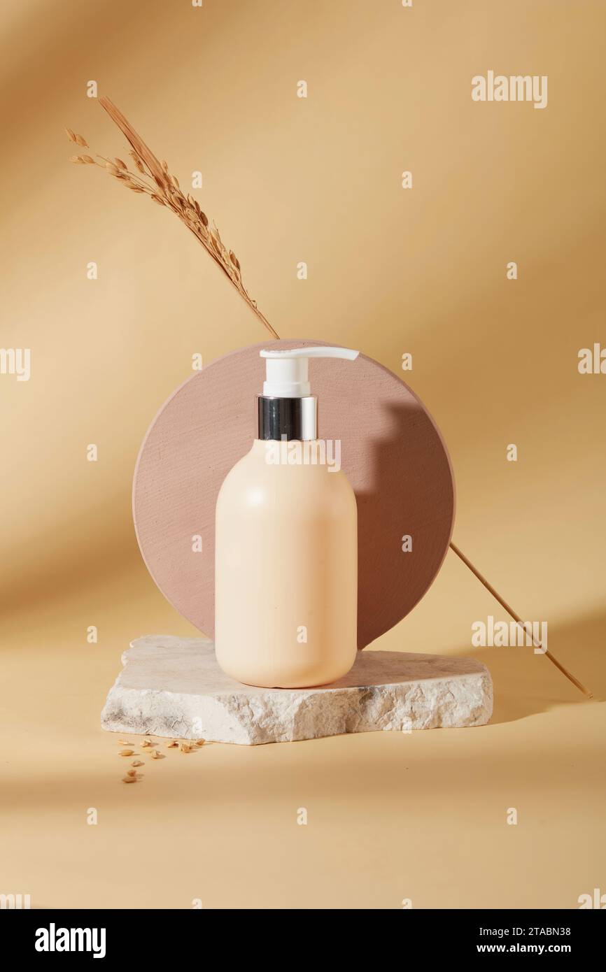 Close-up of a pastel-colored shower gel bottle placed on a stone ...
