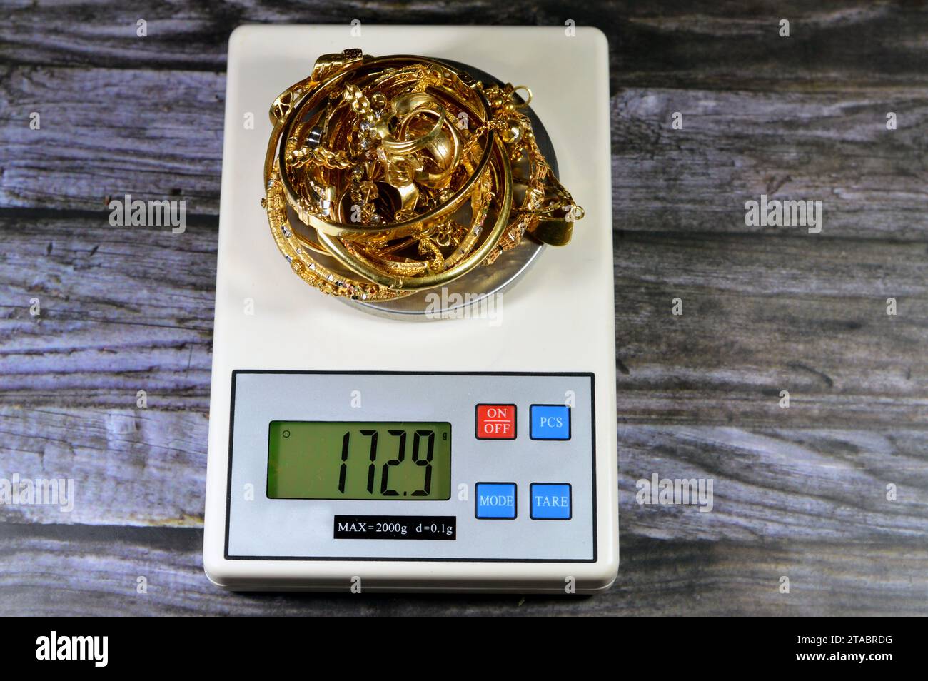 Pile stack of gold on a digital accurate scale in grams, bracelets ...