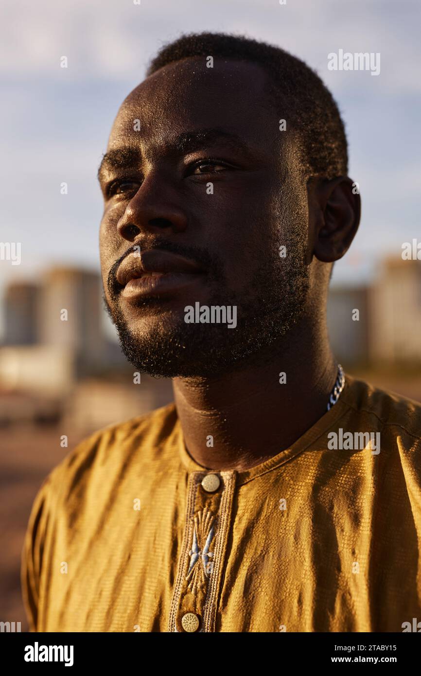 Dramatic portrait of Black young man looking away in half shadow ...