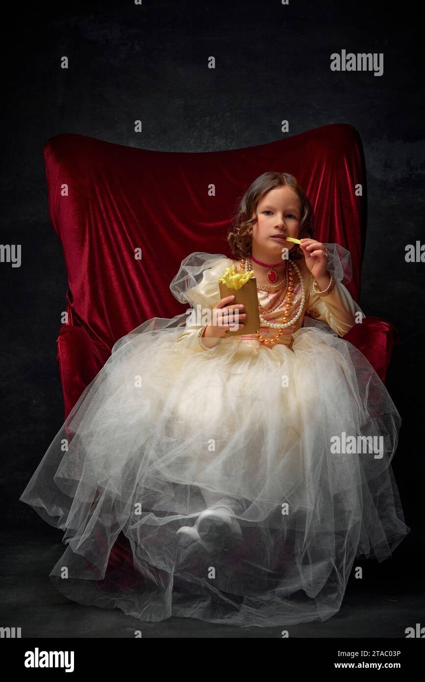 Little princess eating, tasting hot fries potato at fist time sitting ...