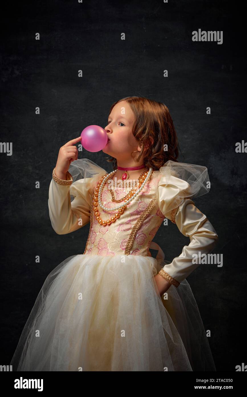 Portrait of small girl as princess against dark vintage background ...