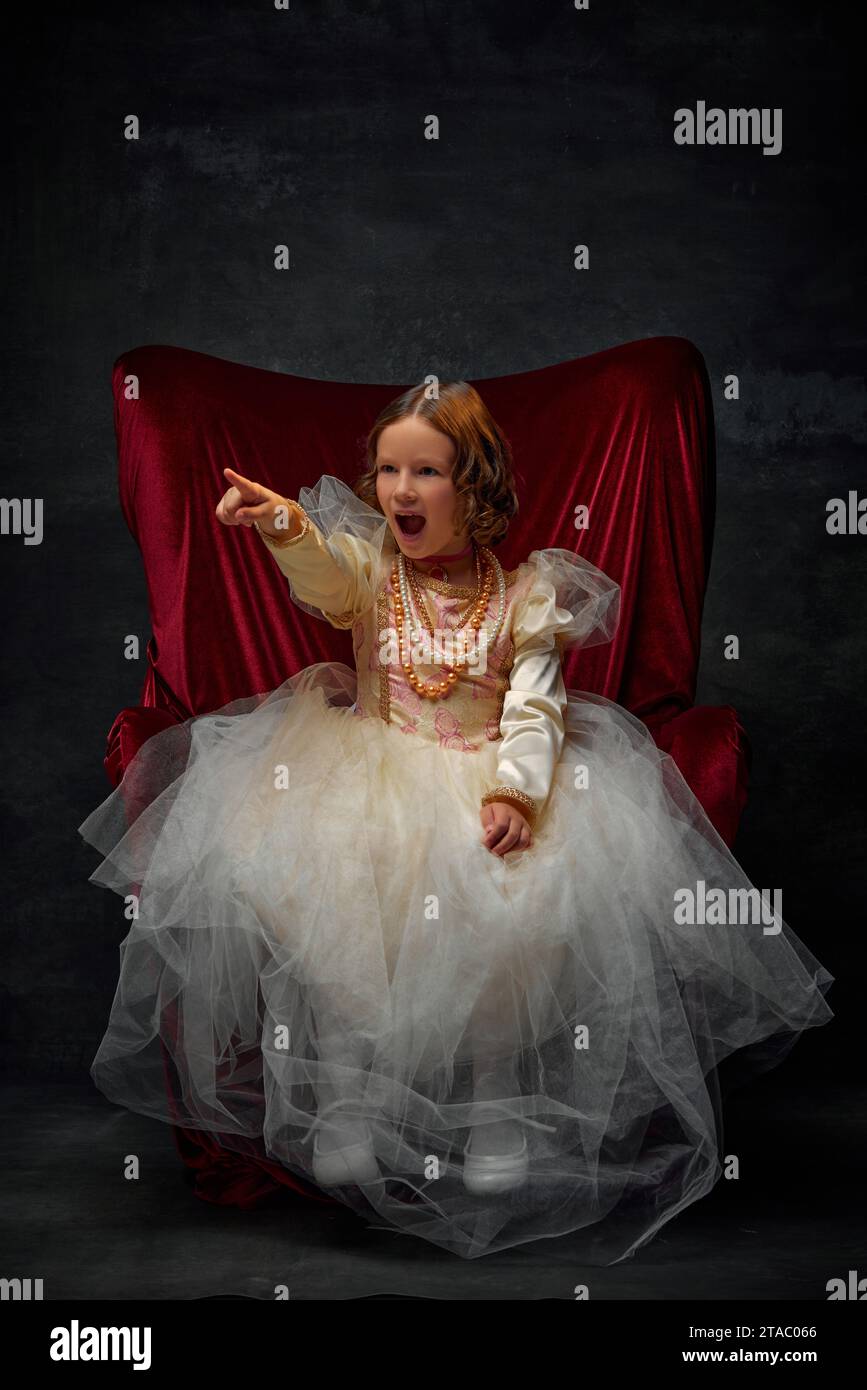 Get out. Little girl sitting on throne wearing in old-fashioned dress ...