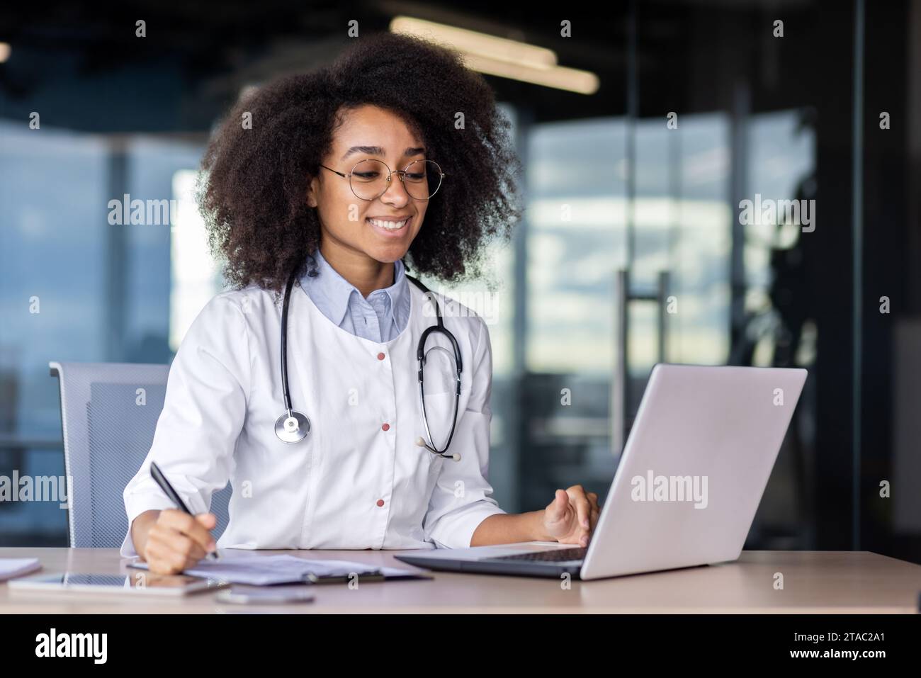 Woman doctor at the workplace inside the office, working with a laptop ...