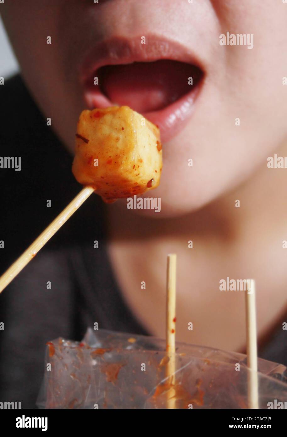 Woman happily eating sausage on blurred background Stock Photo - Alamy