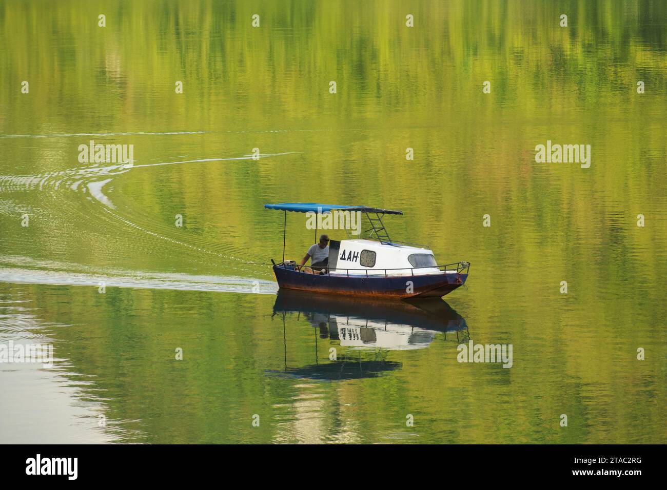 small cabin boat sailing on the water reflection of Perucac Lake ...