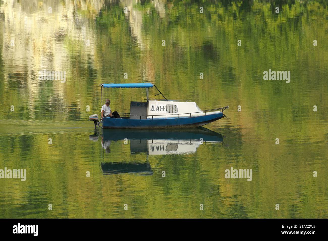 small cabin boat sailing on the water reflection of Perucac Lake ...