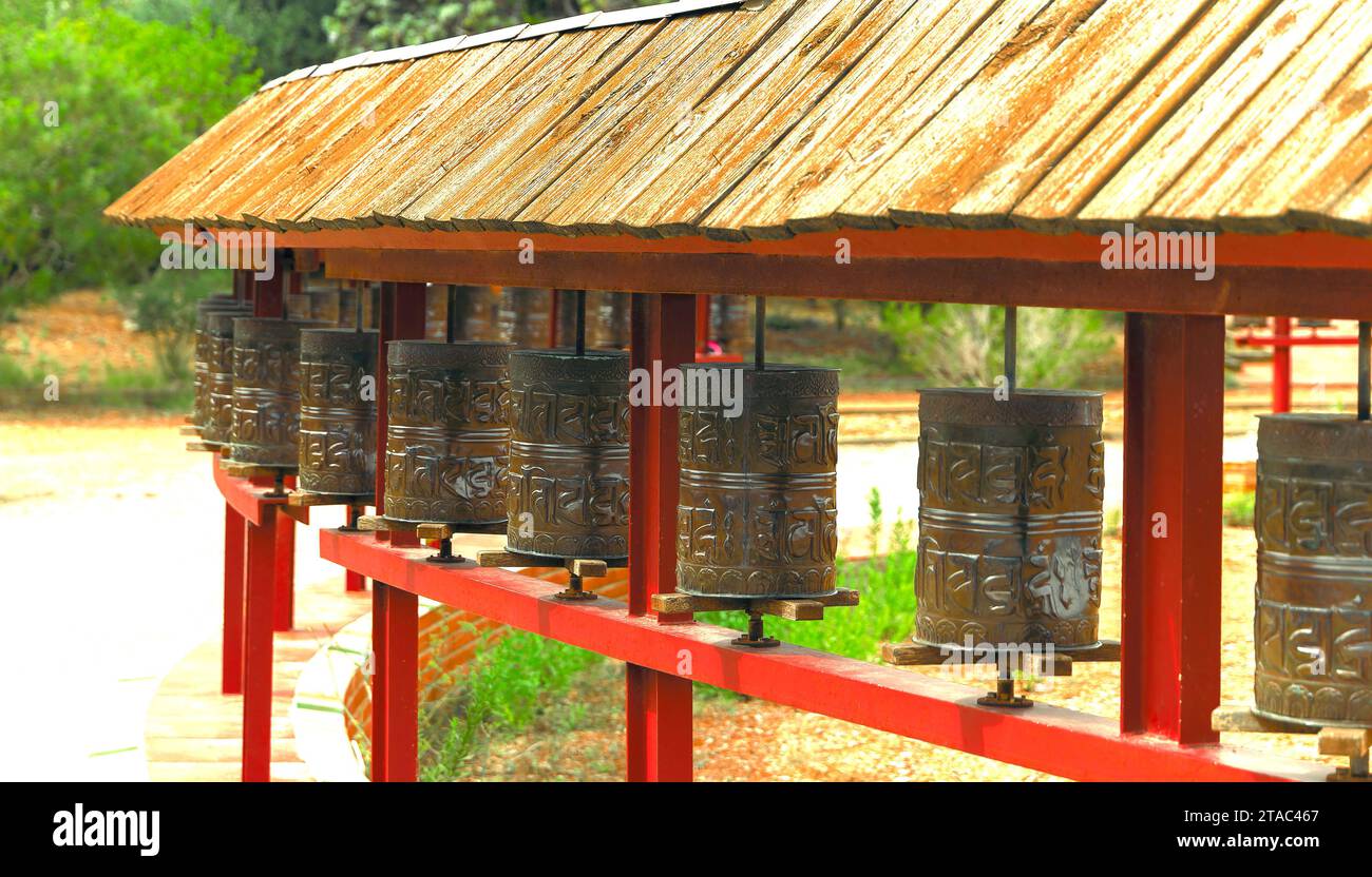 Row of prayer wheels under a wooden roof at the Garraf Sakya Tashi Ling ...