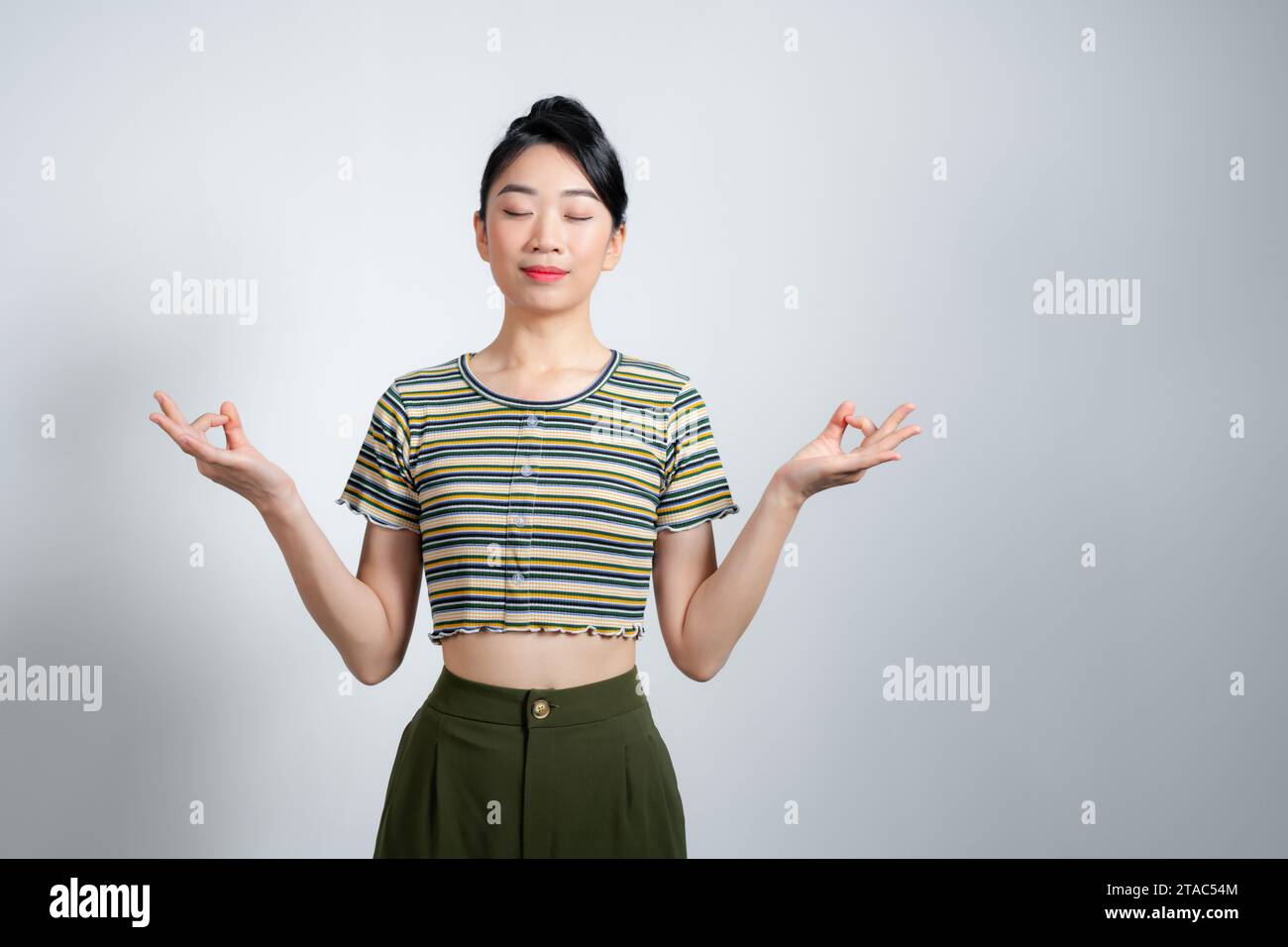 Portrait of calm beautiful woman holding hands up in mudra gesture ...