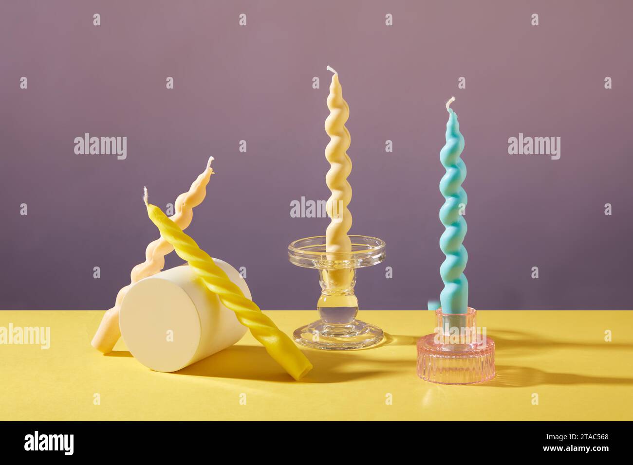 Two twisted candles are placed on glass candlesticks, two others are ...
