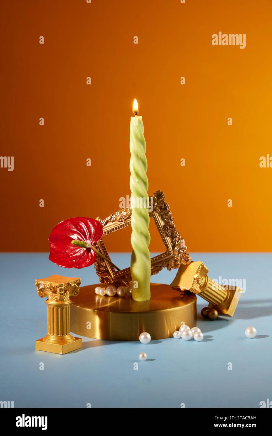 Front view of a burning candle displayed with vintage props on a blue ...