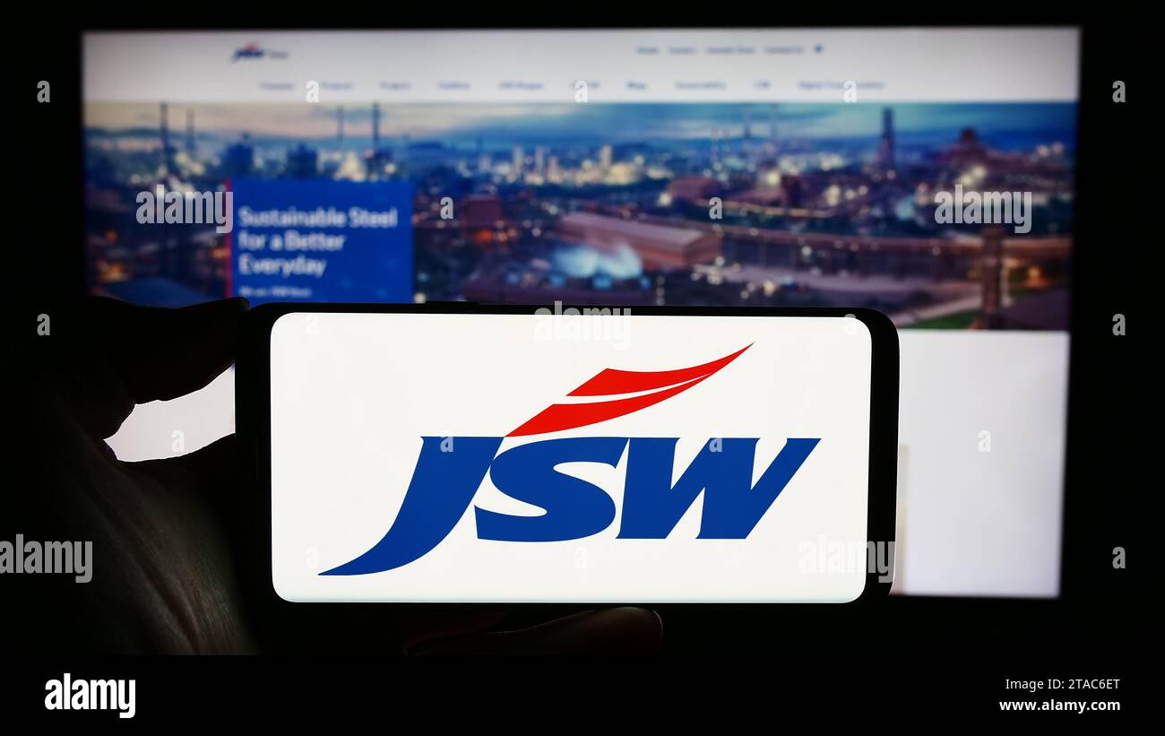 Person holding mobile phone with logo of Indian conglomerate JSW Group ...
