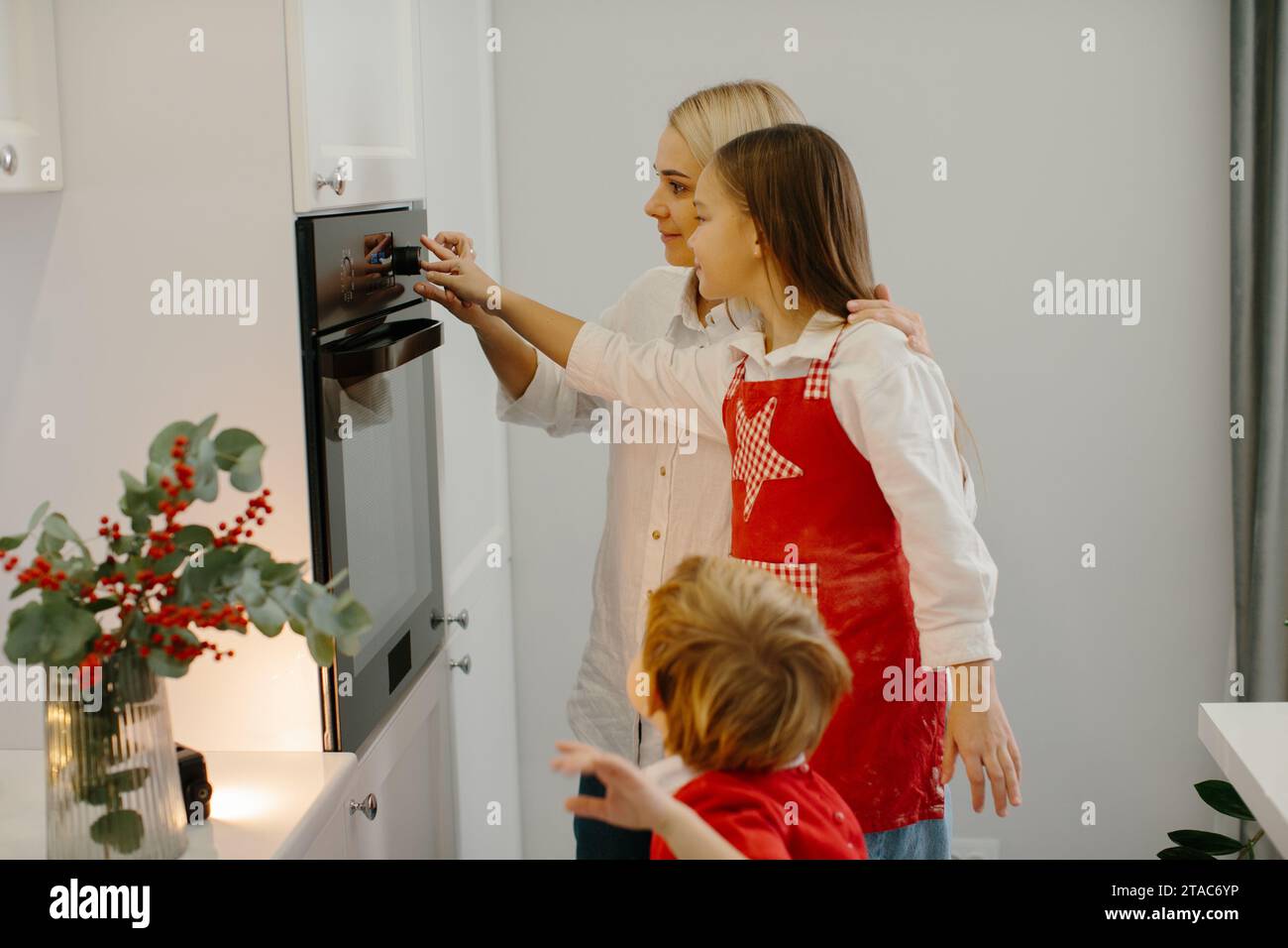 Mother and children bake Christmas gingerbread in a modern kitchen. Mom ...