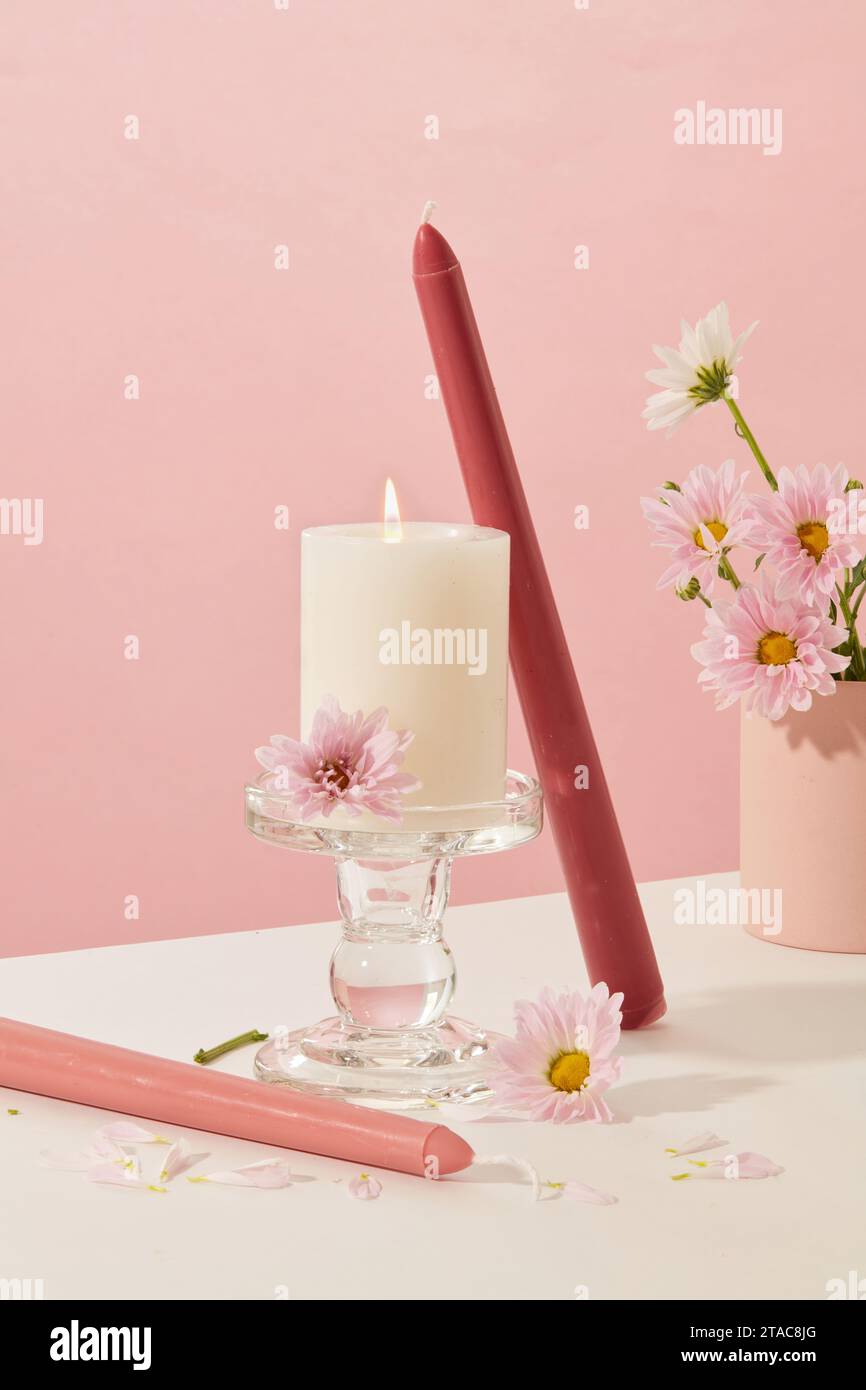 Front view of burning candle is placed on a glass candlestick. The ...