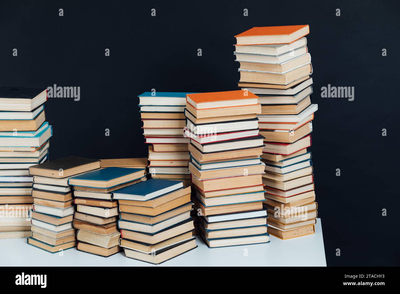 Lots of stacks of old educational books on black background library ...