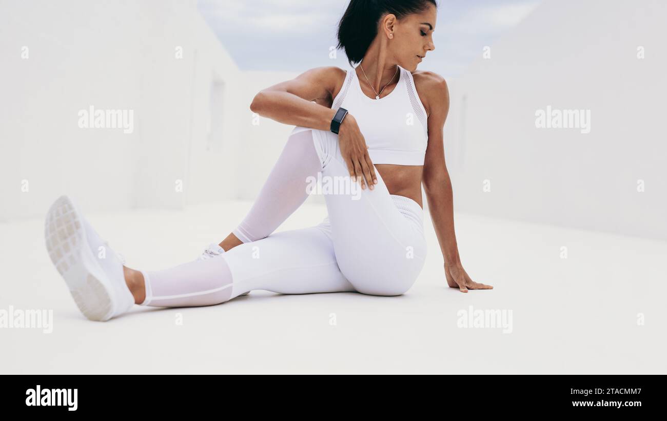 Fitness woman sitting on floor and twisting her back sideways. Woman in ...