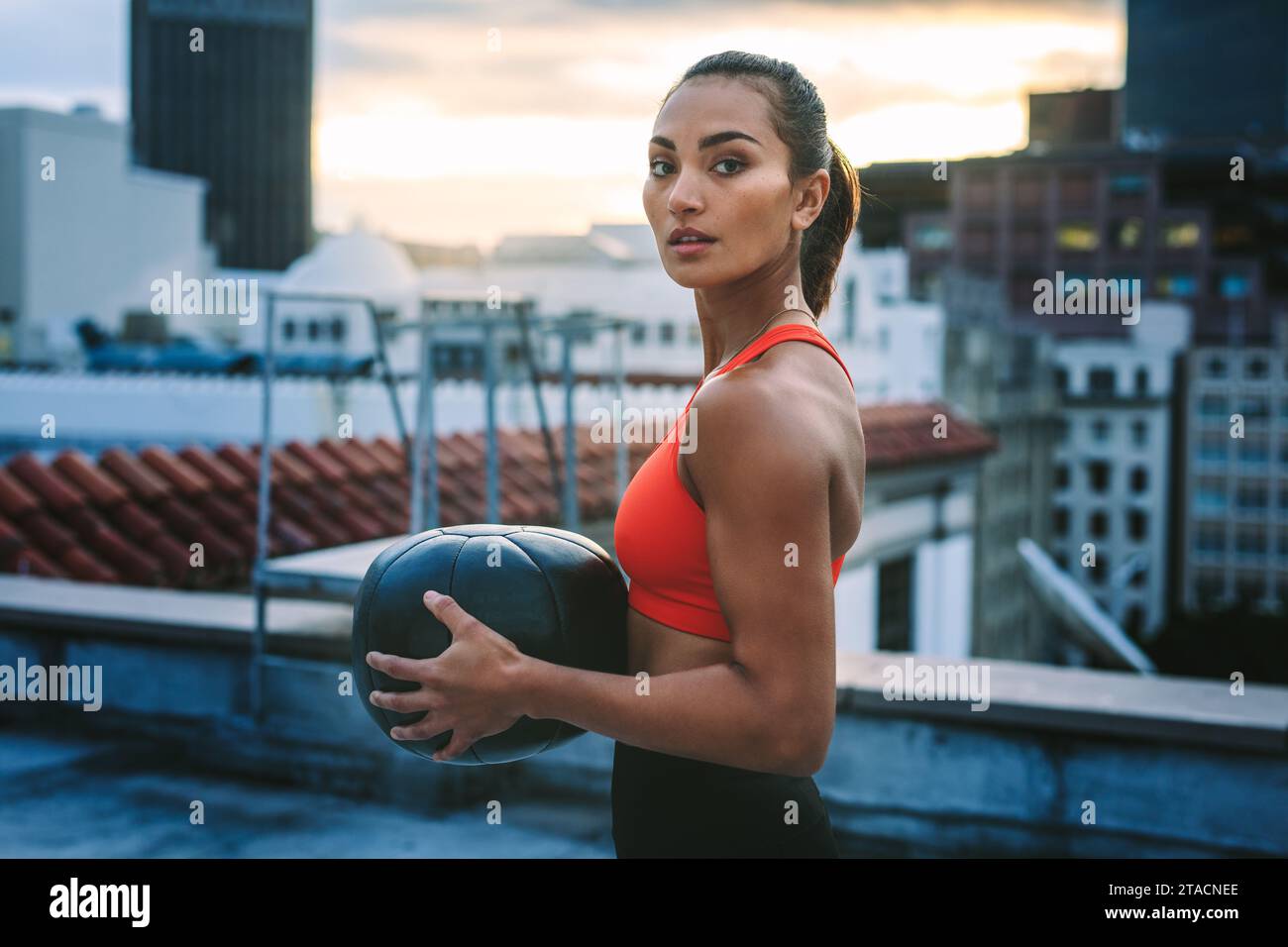Fitness woman standing on the terrace of a building doing workout using ...
