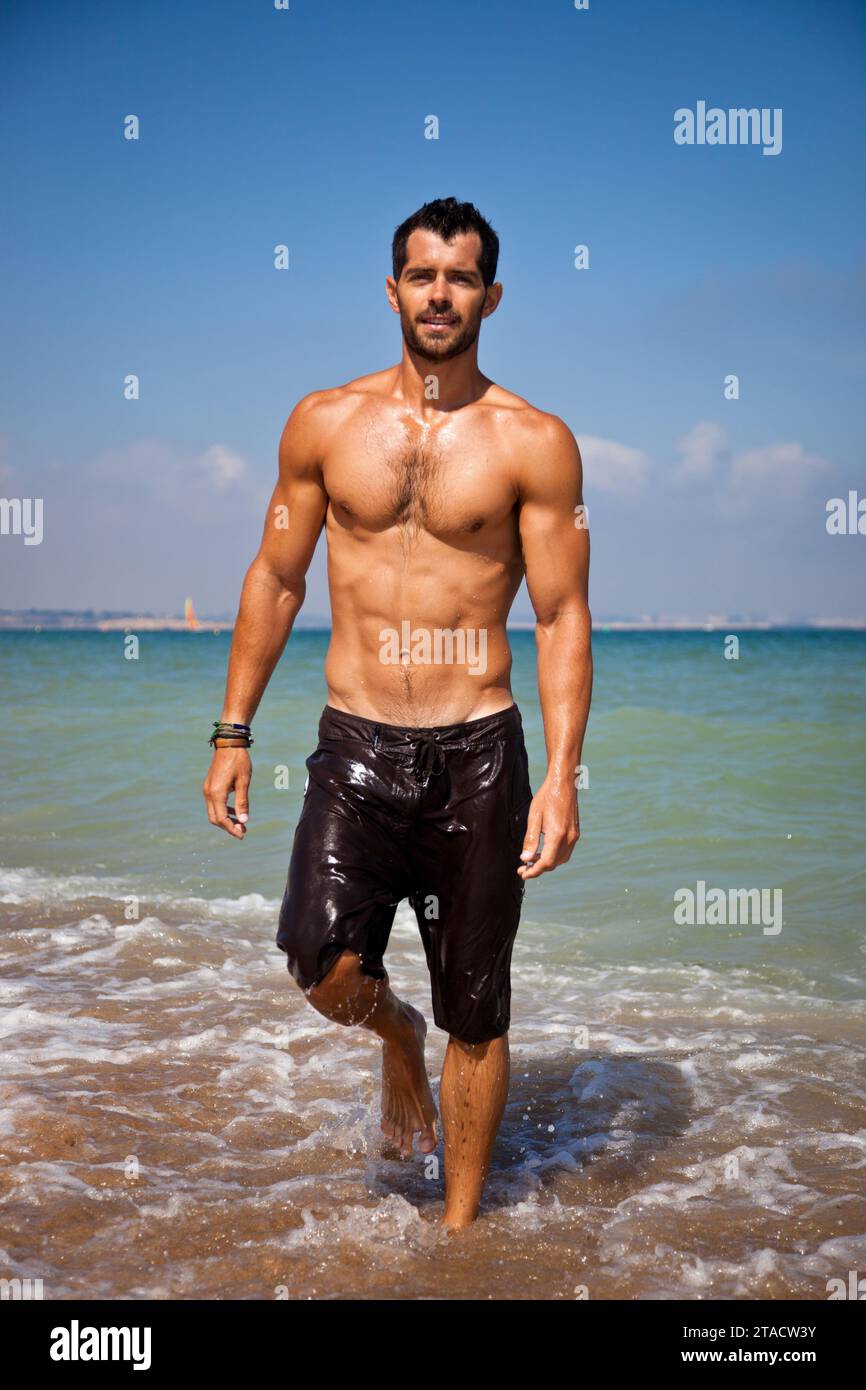 Handsome muscular man walking out of the water on a turquoise water ...