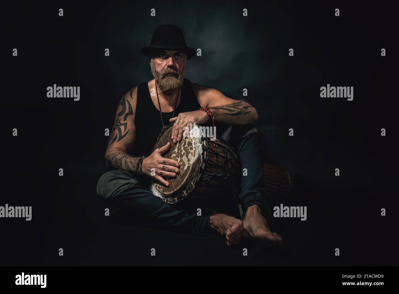 man playing an african djembe, studio photography, black background ...