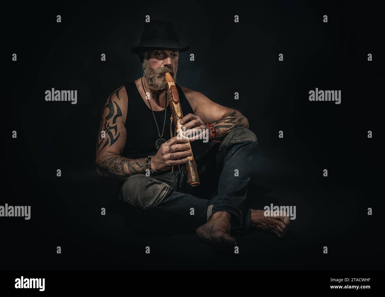 Man plays a native american flute in a studio, atelier photos, black ...