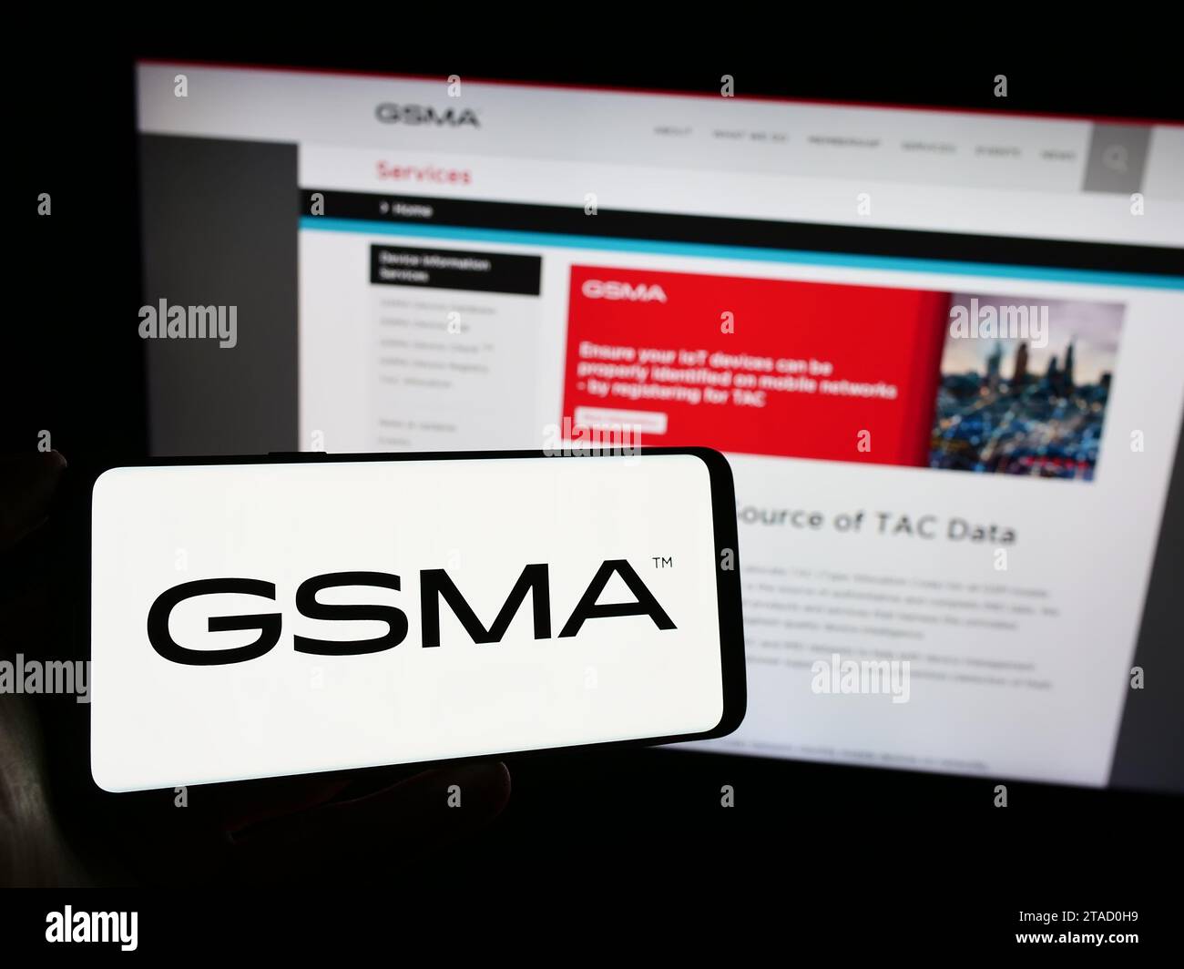 Person holding cellphone with logo of mobile industry organisation GSM Association (GSMA) in ...