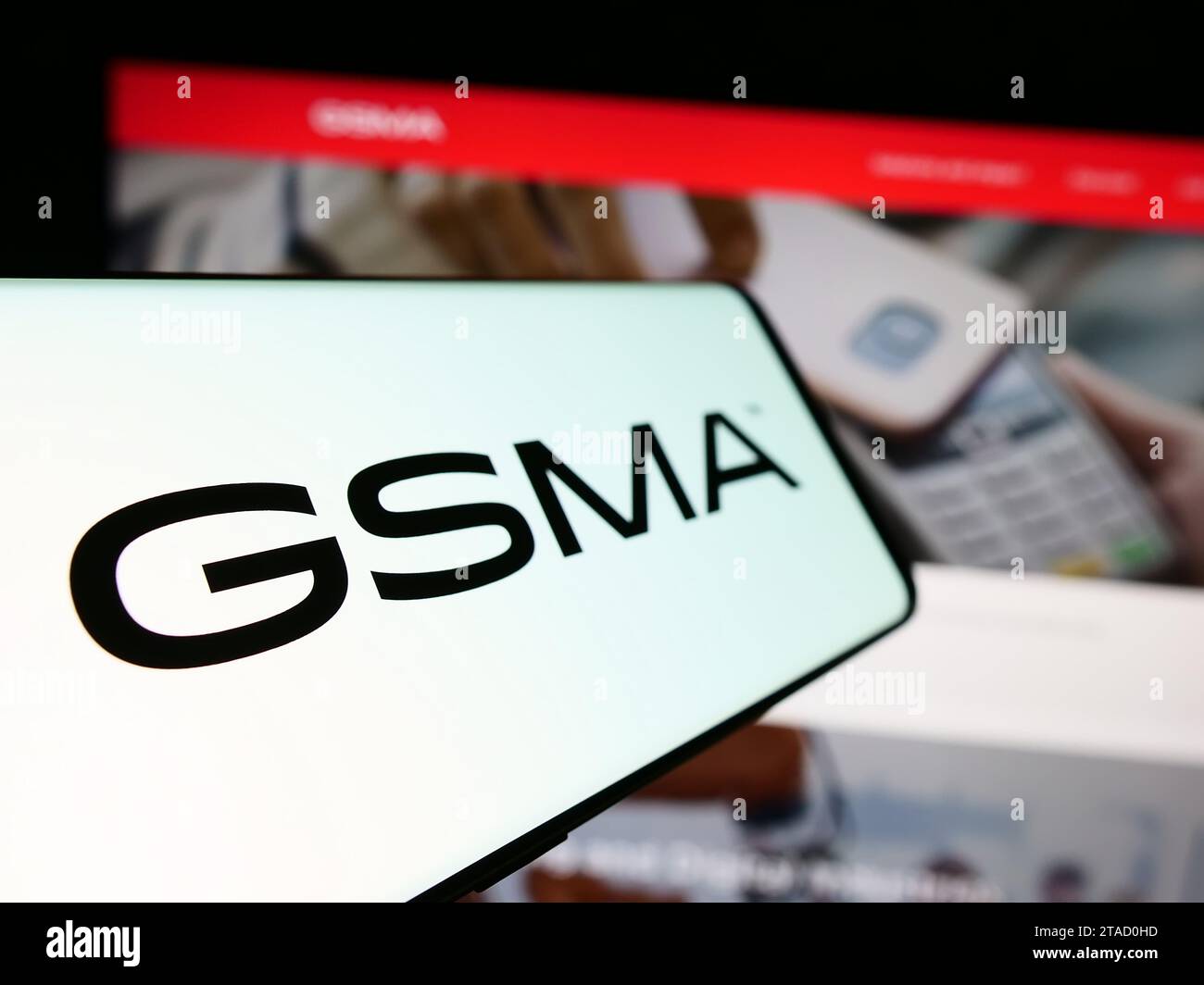 Smartphone with logo of mobile industry organisation GSM Association (GSMA) in front of business ...