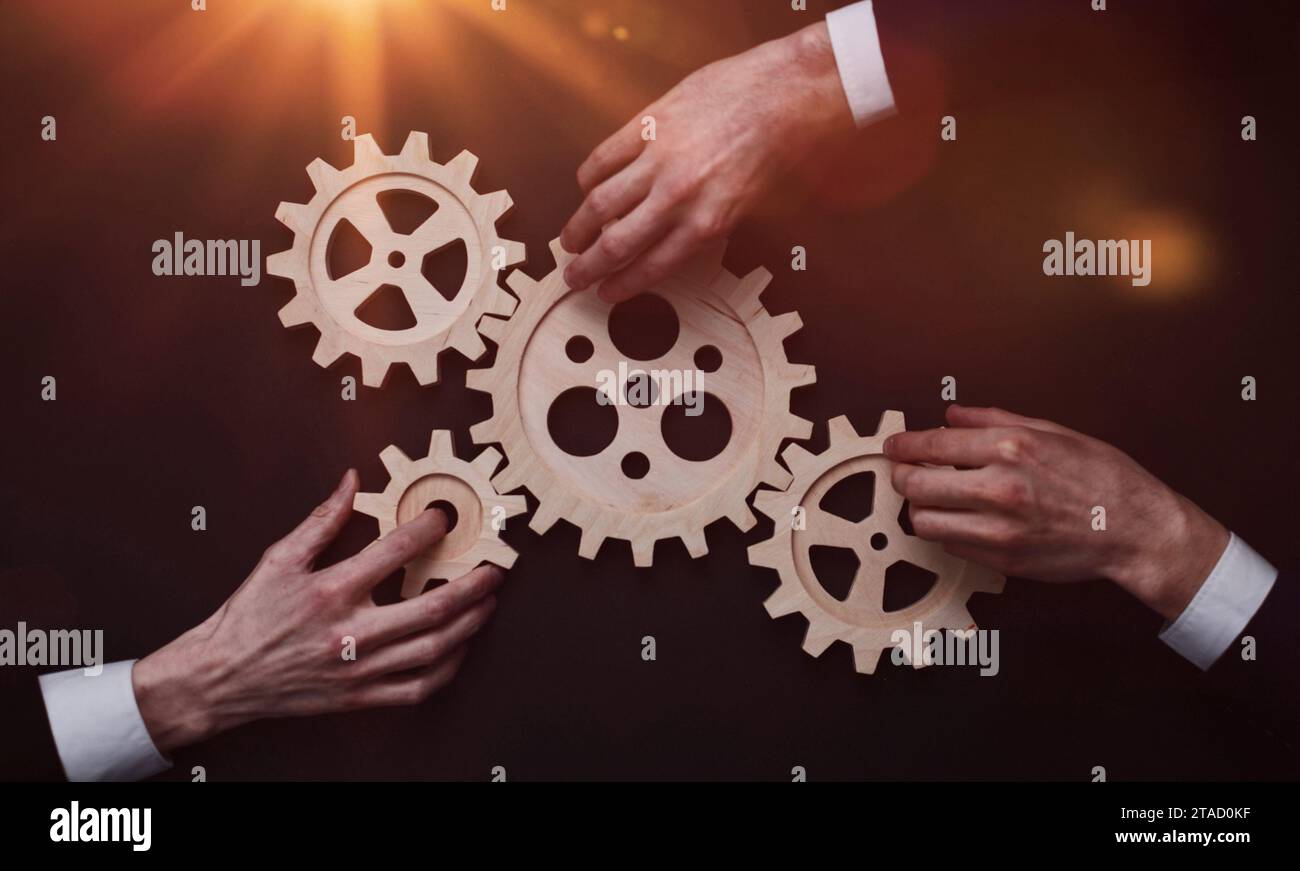 Group of business people connecting wooden cogwheels together on black ...