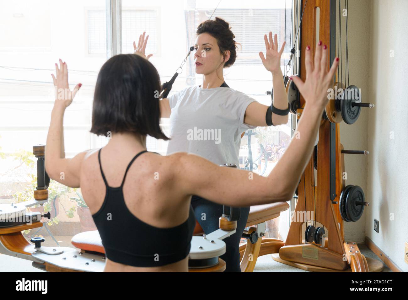 female instructor and student are sitting on exercise machine at home ...