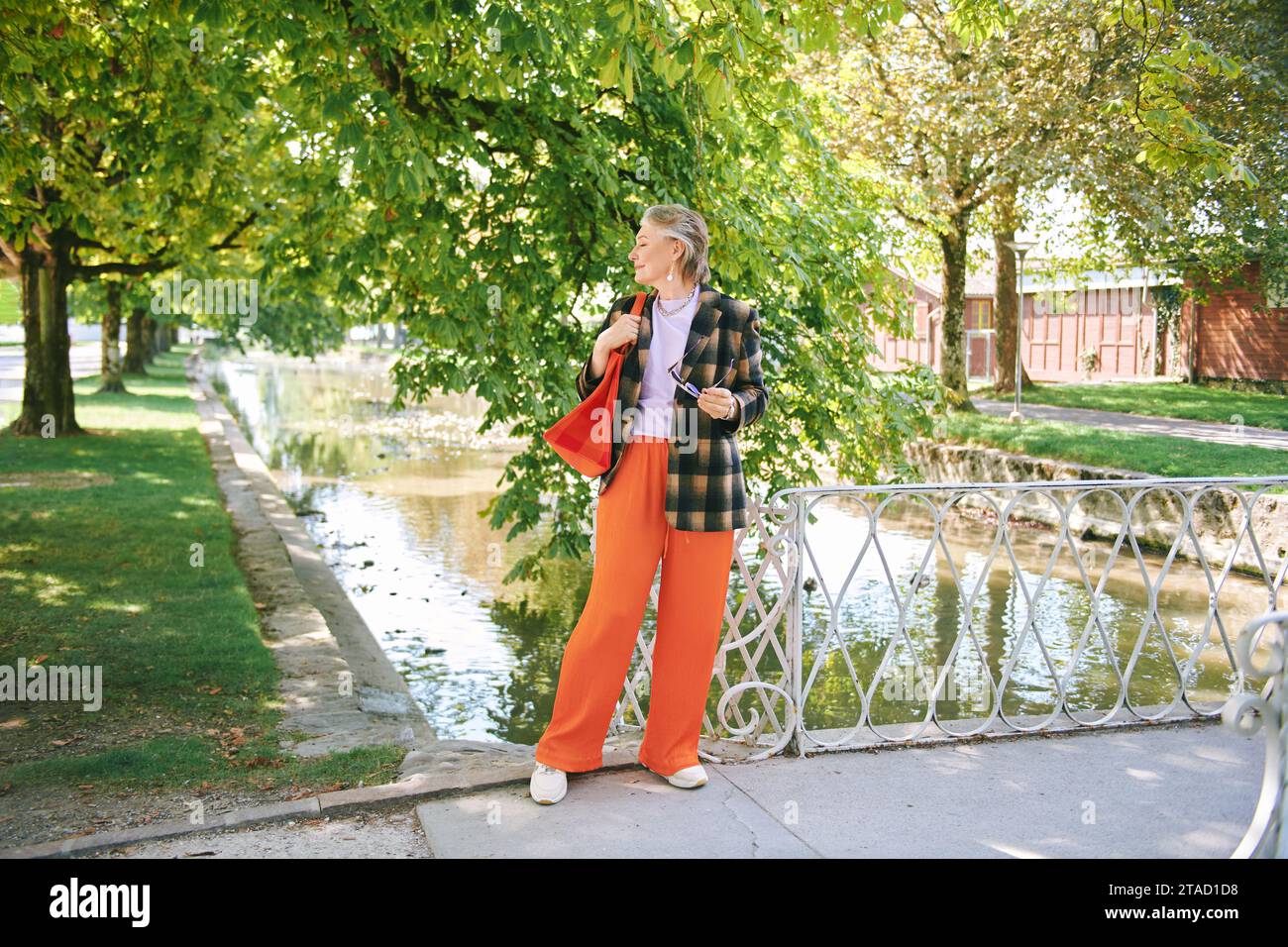 Outdoor portrait of beautiful and elegant middle age 55 - 60 year old woman, wearing bright ...