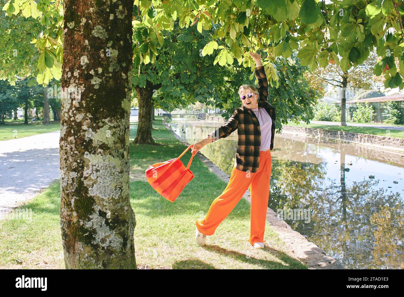 Outdoor portrait of beautiful and elegant middle age 55 - 60 year old woman, wearing bright ...