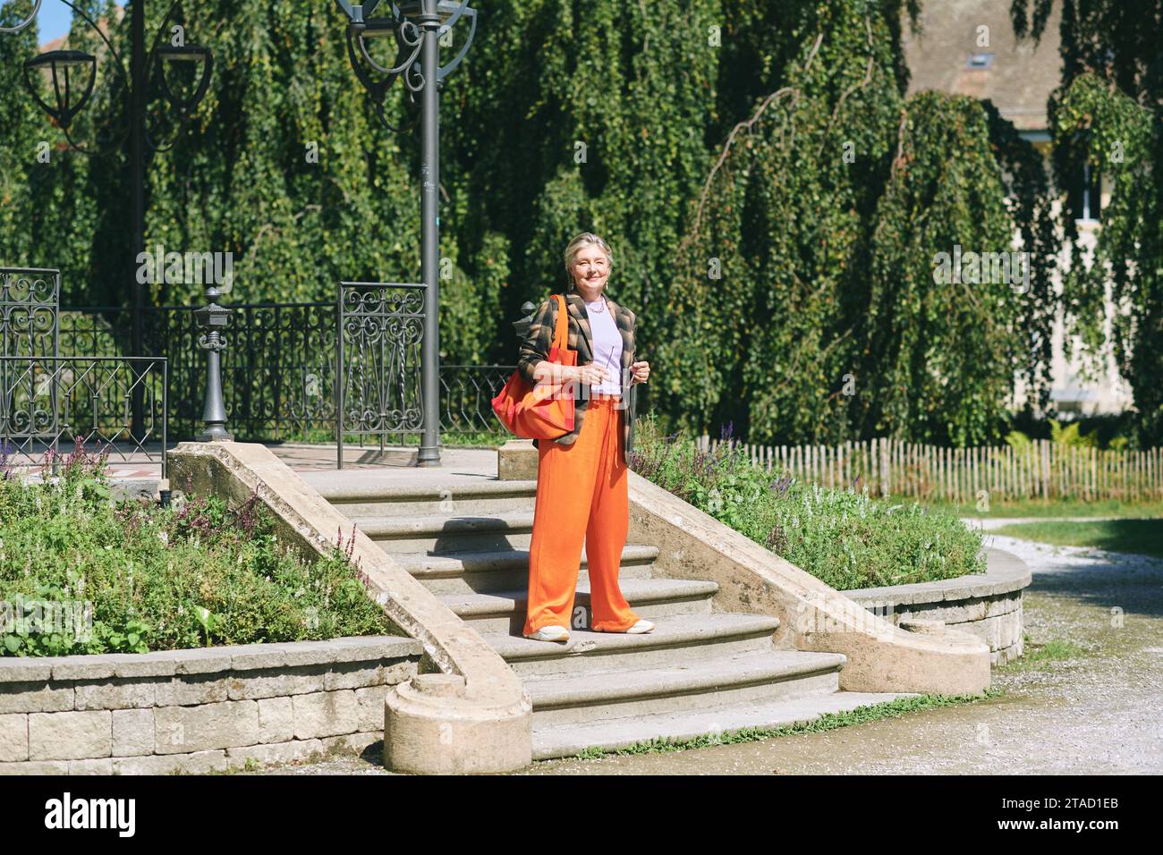 Outdoor portrait of beautiful and elegant middle age 55 - 60 year old woman, wearing bright ...