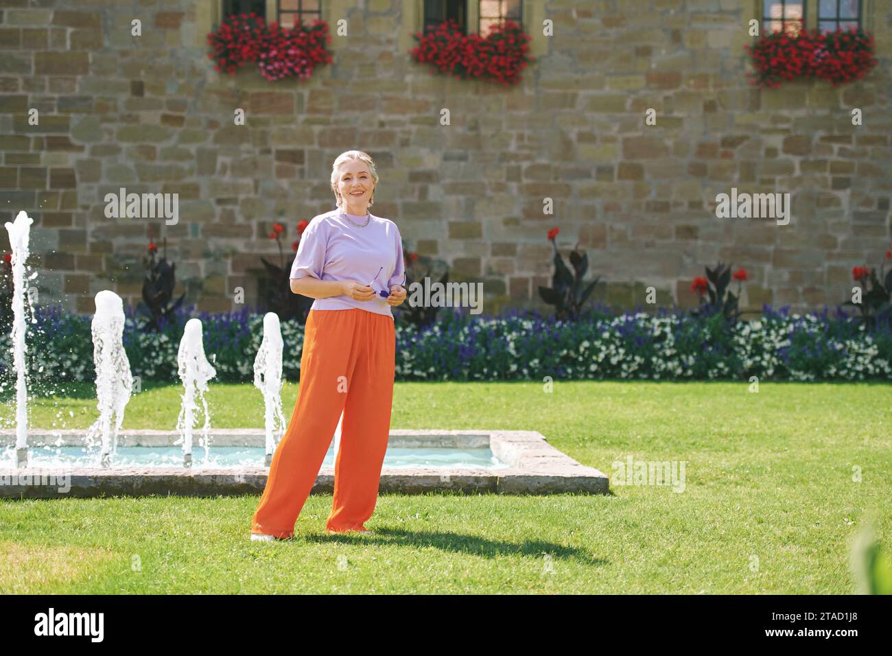 Outdoor portrait of beautiful and elegant middle age 55 - 60 year old woman, wearing bright ...