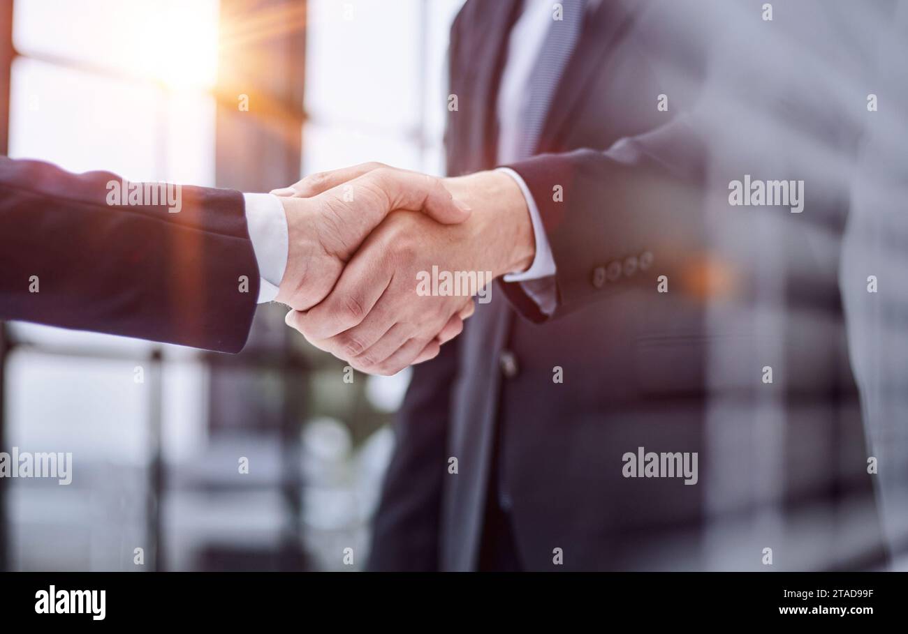 executives shaking hands in front of their manager and a colleague ...