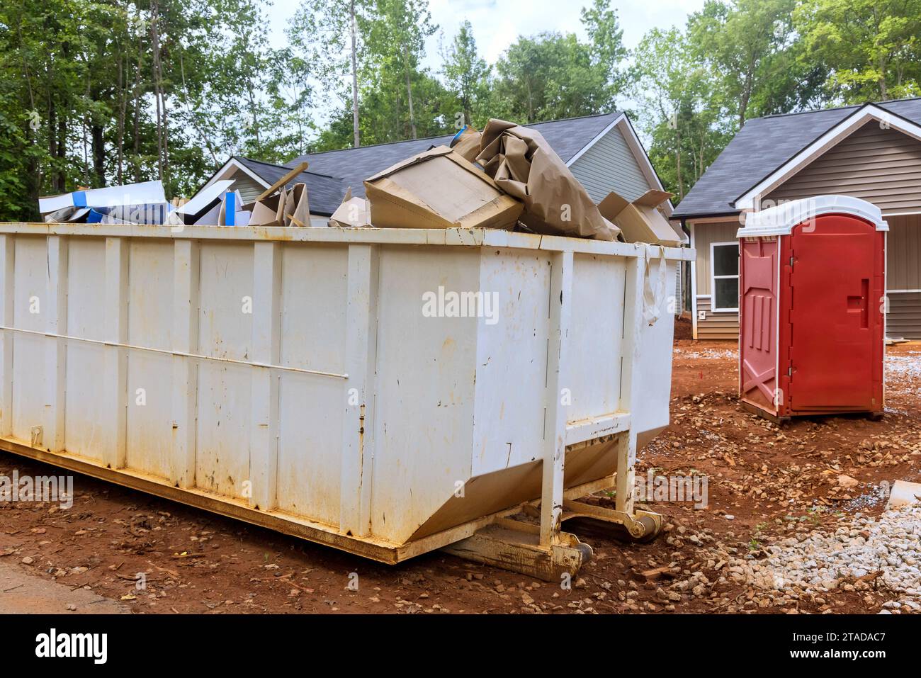 Dumpster full of construction waste debris is positioned near ...