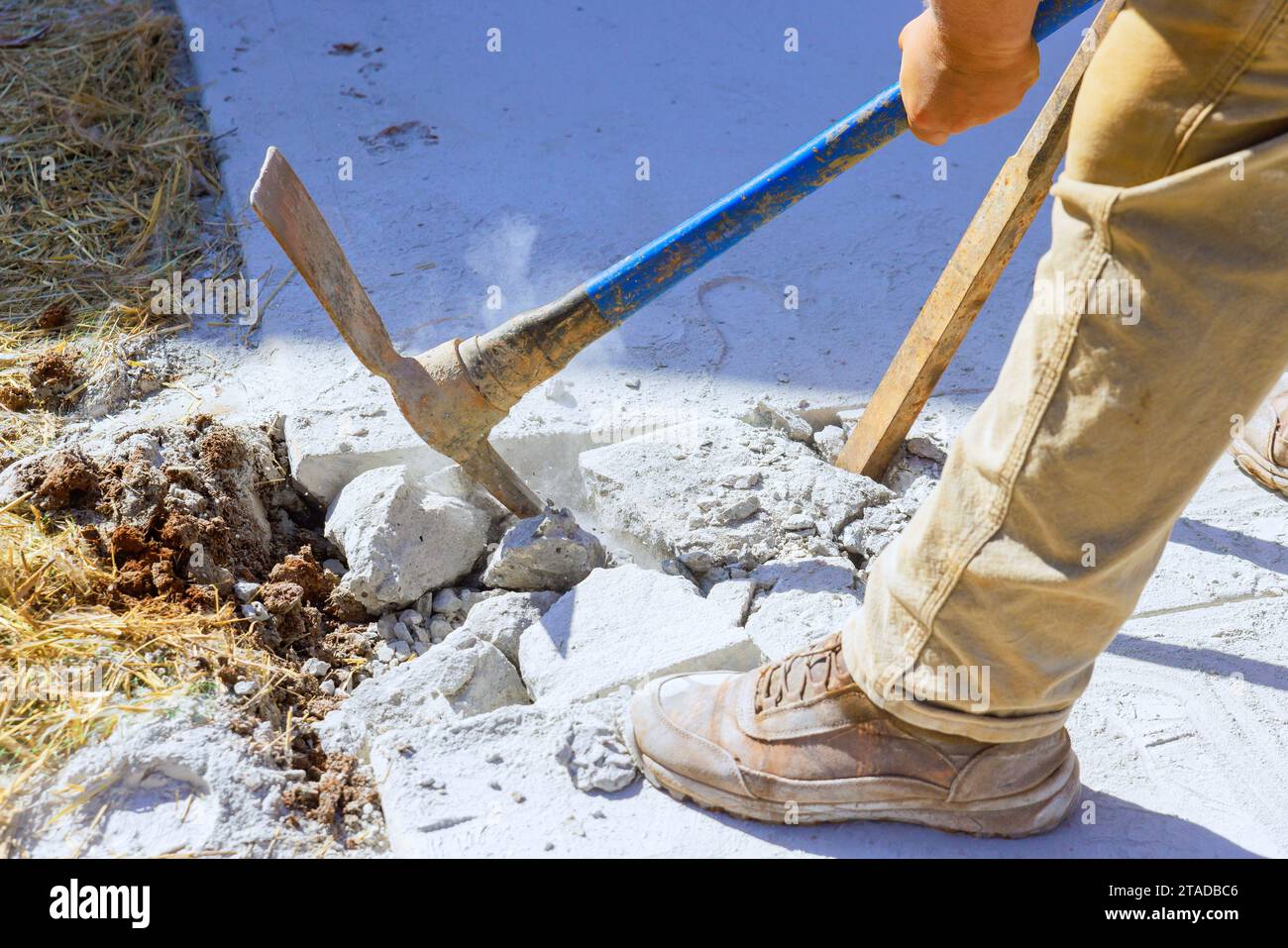 Worker smashes concrete old driveway with pickaxe on construction site ...