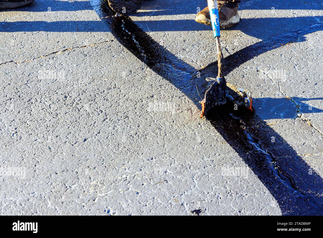 During worker patcher performs coated filling asphalt cracks sealing ...