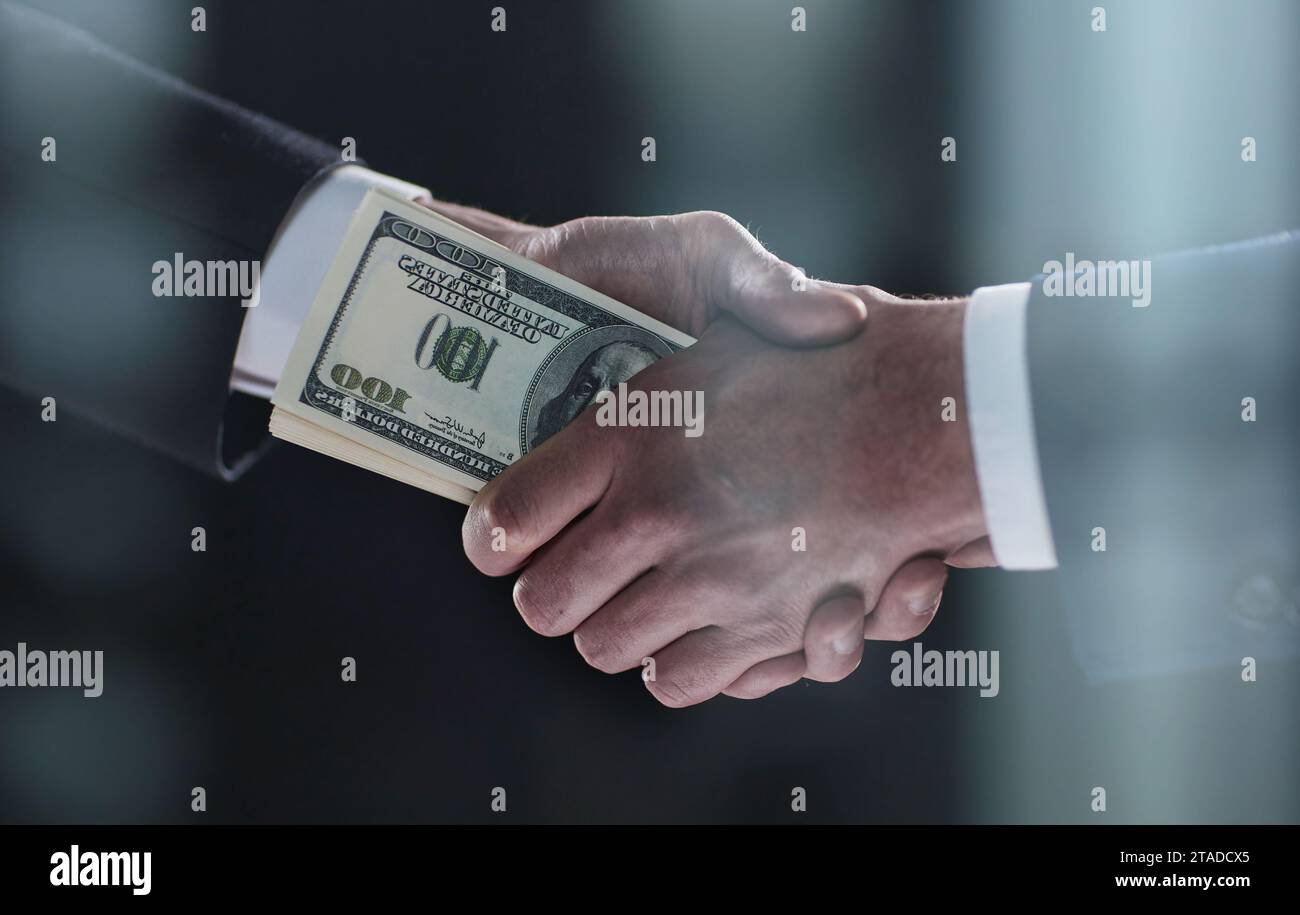 Handshake with the transfer of money on a black background Stock Photo ...