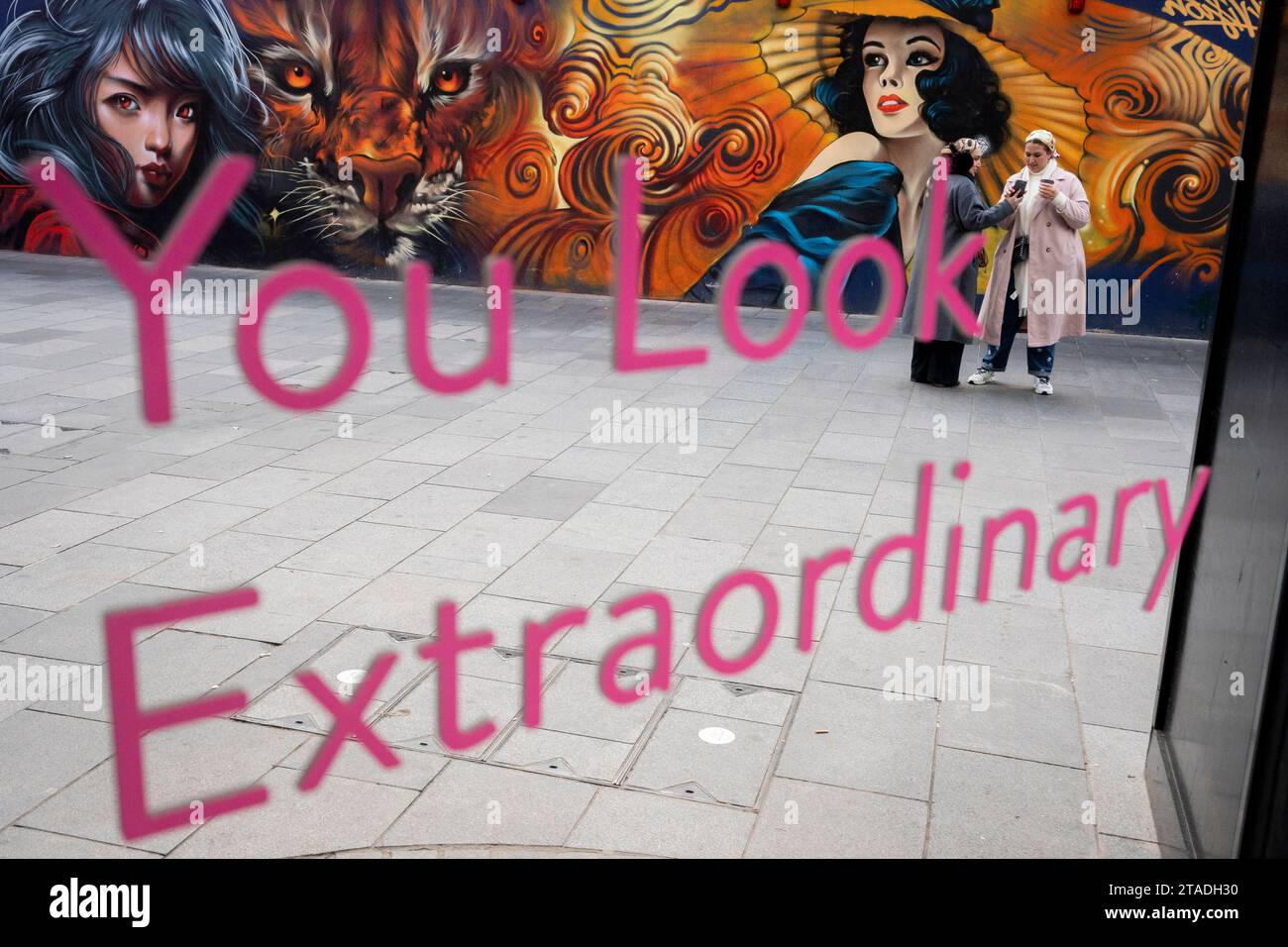 Two women look at each others' phones aftrer taking selfies in front of ...