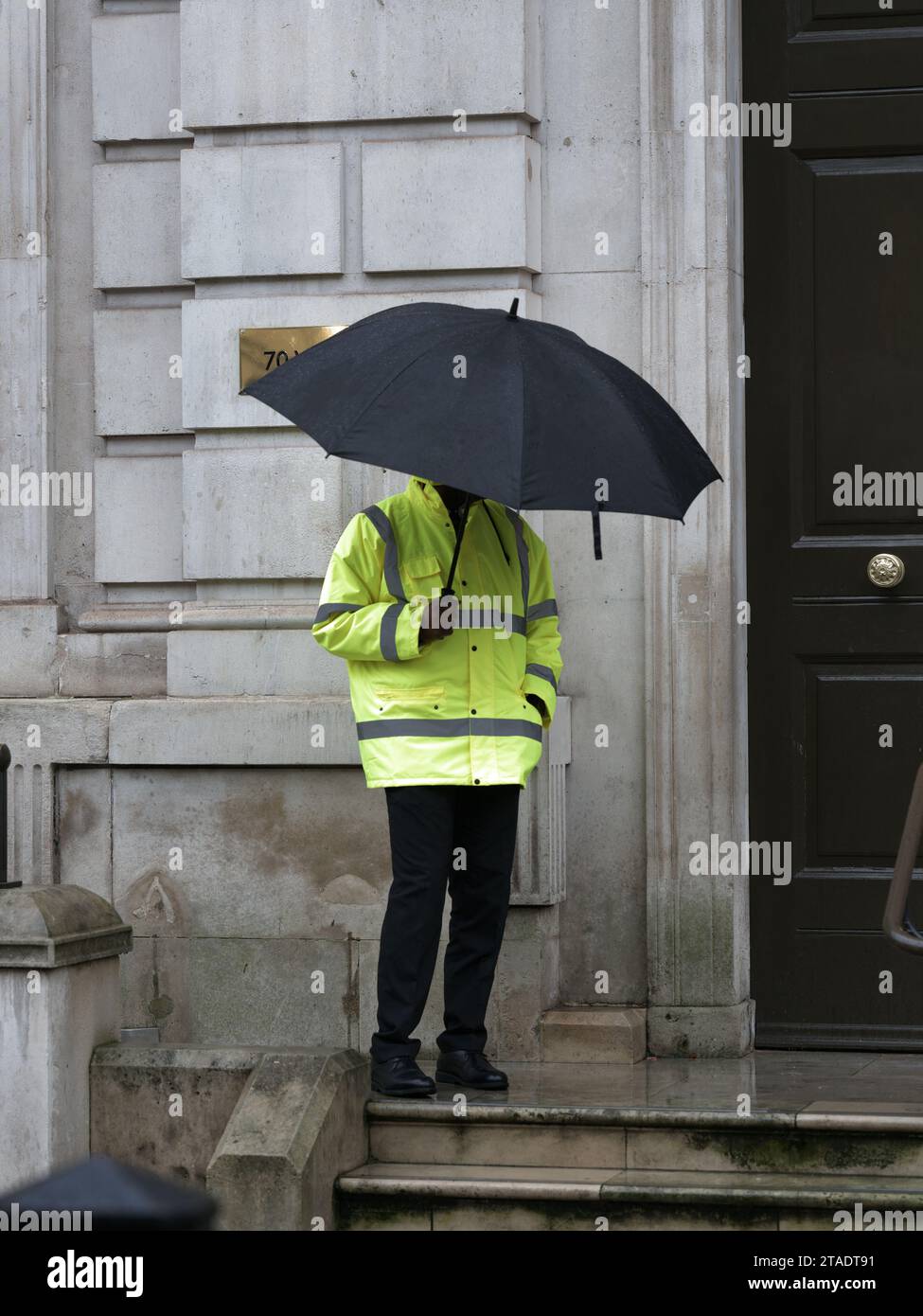 Security guard with umbrella at an entrance to the british Government's ...