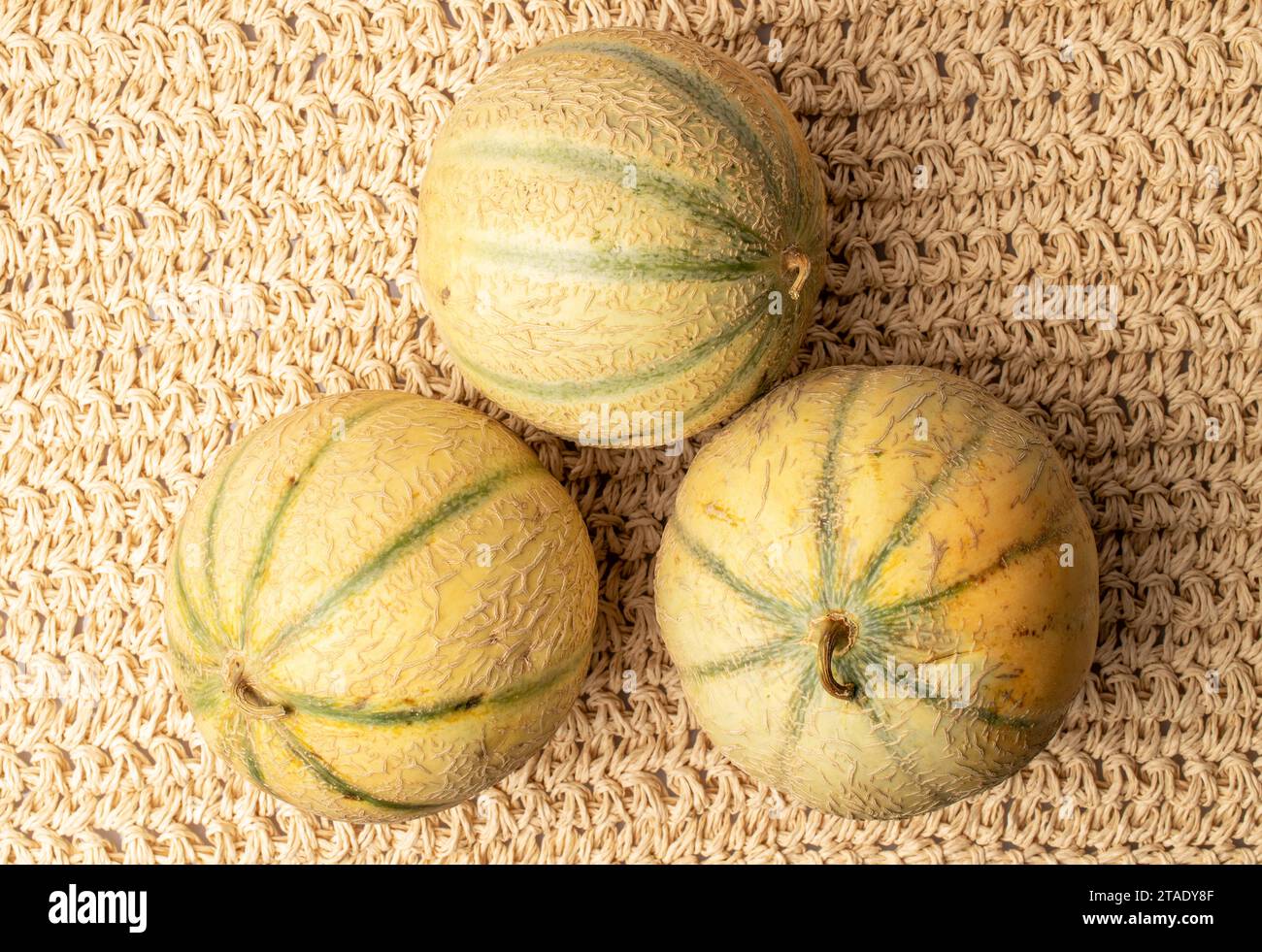 Three fragrant juicy, organic melons, close-up, on a straw mat, top ...