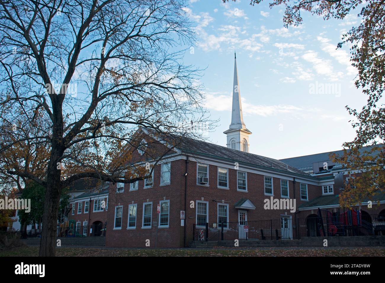White spire of church protruding into partially clouded blue sky in ...
