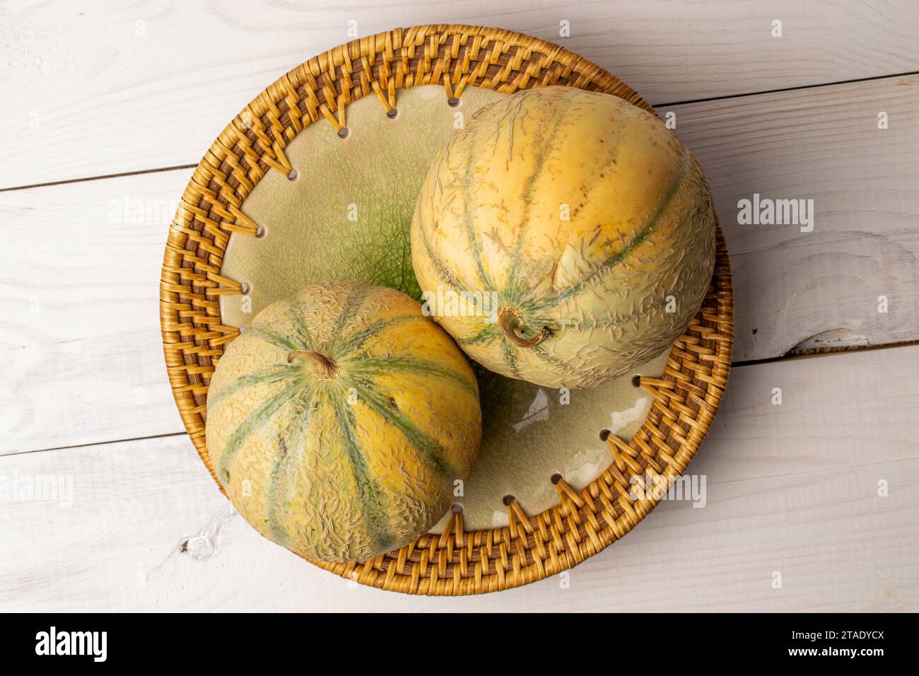 Two fragrant organic melons on a ceramic plate, close-up, on a white ...