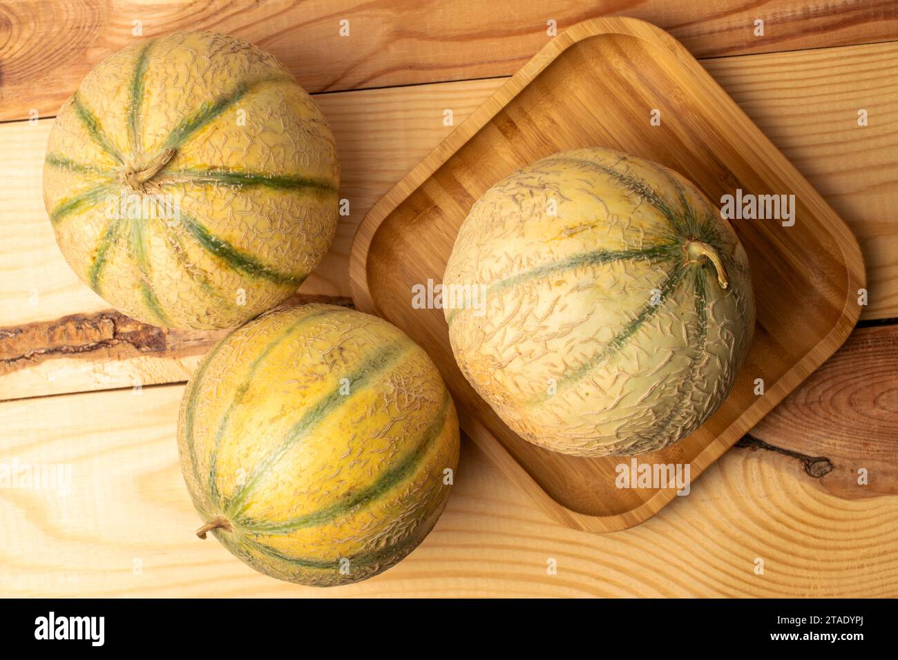 Three fragrant juicy, organic melons, with a bamboo tray, close-up, on ...