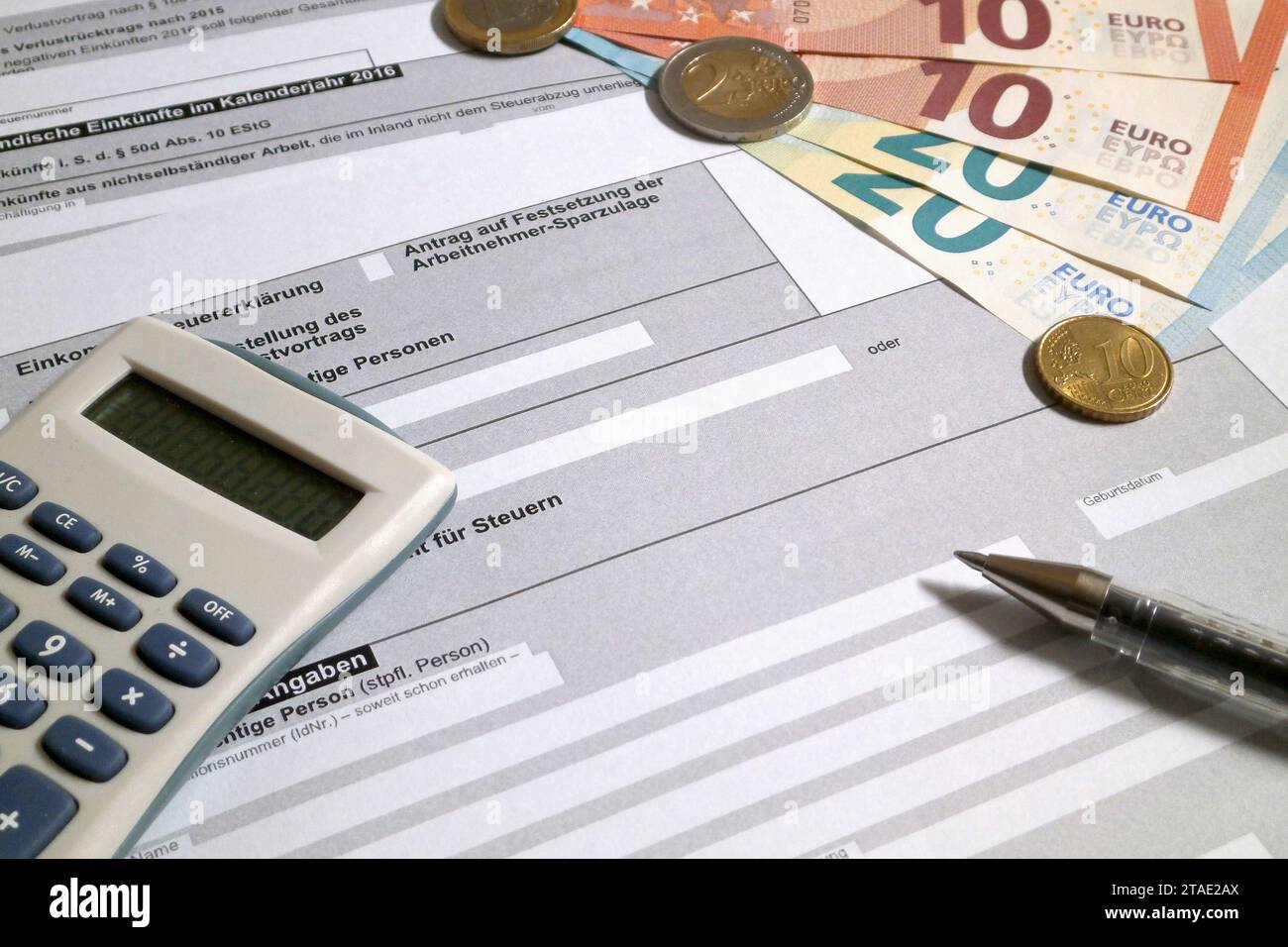 A ballpoint pen, a calculator, some euro coins and euro banknotes on ...