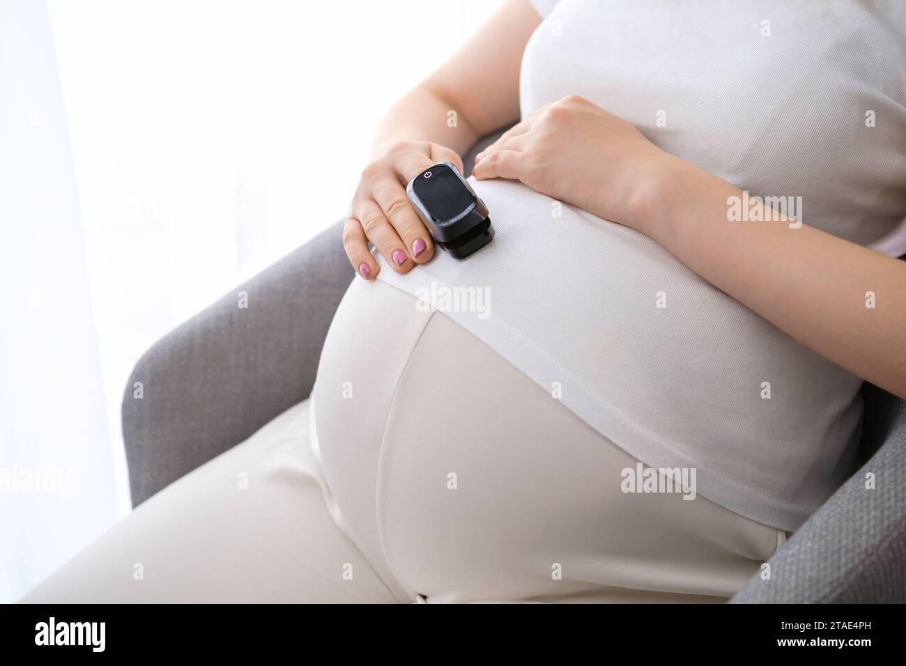 A pregnant woman measures the pulse with a heart rate monitor ...